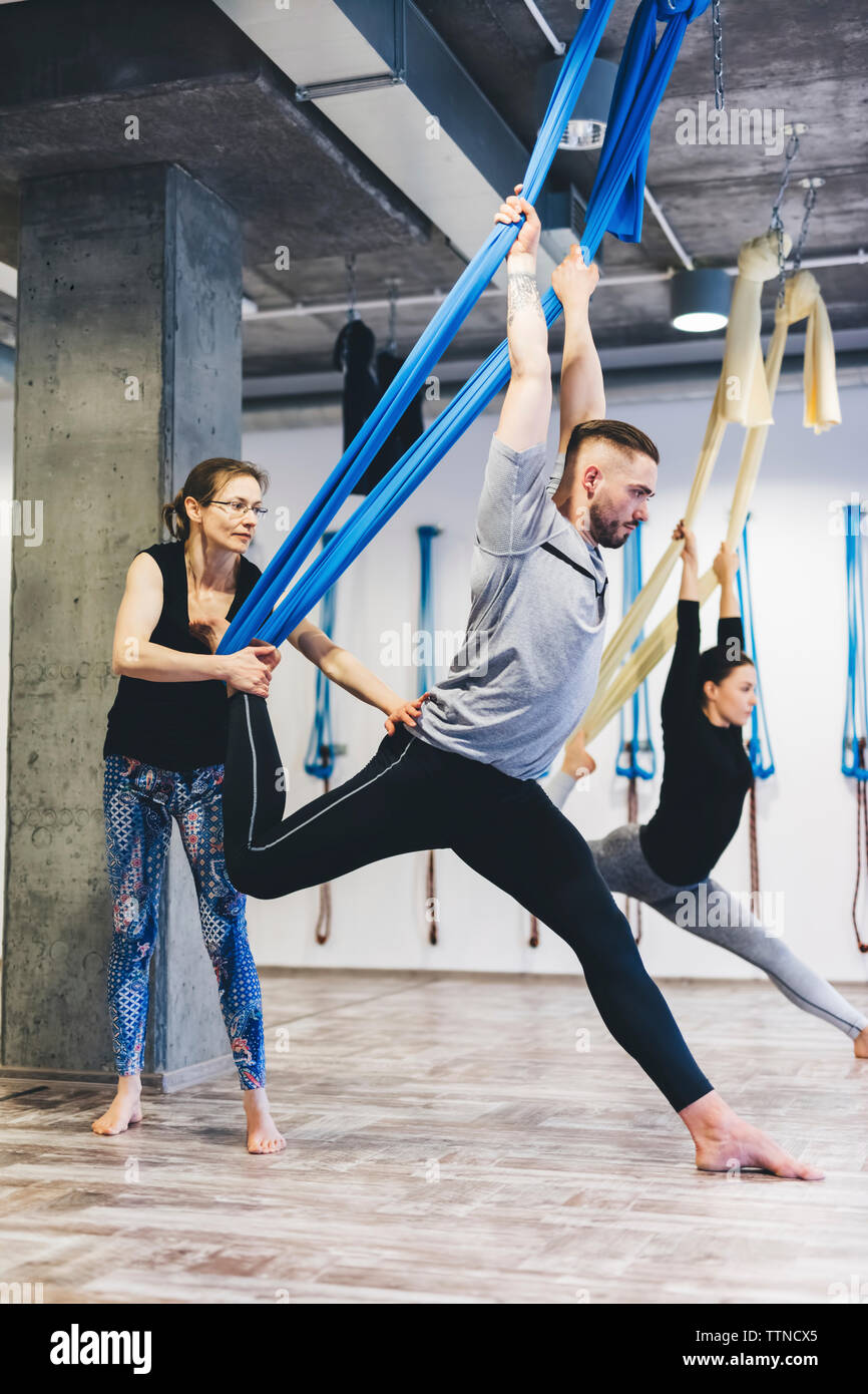 Full length of instructor with fitness class performing step aerobics ...