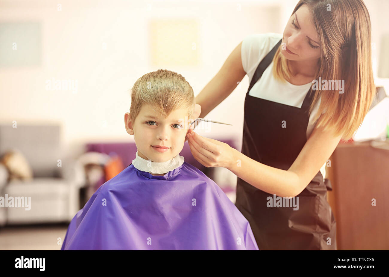 Hairdresser making hairstyle to child on blurred background Stock Photo ...