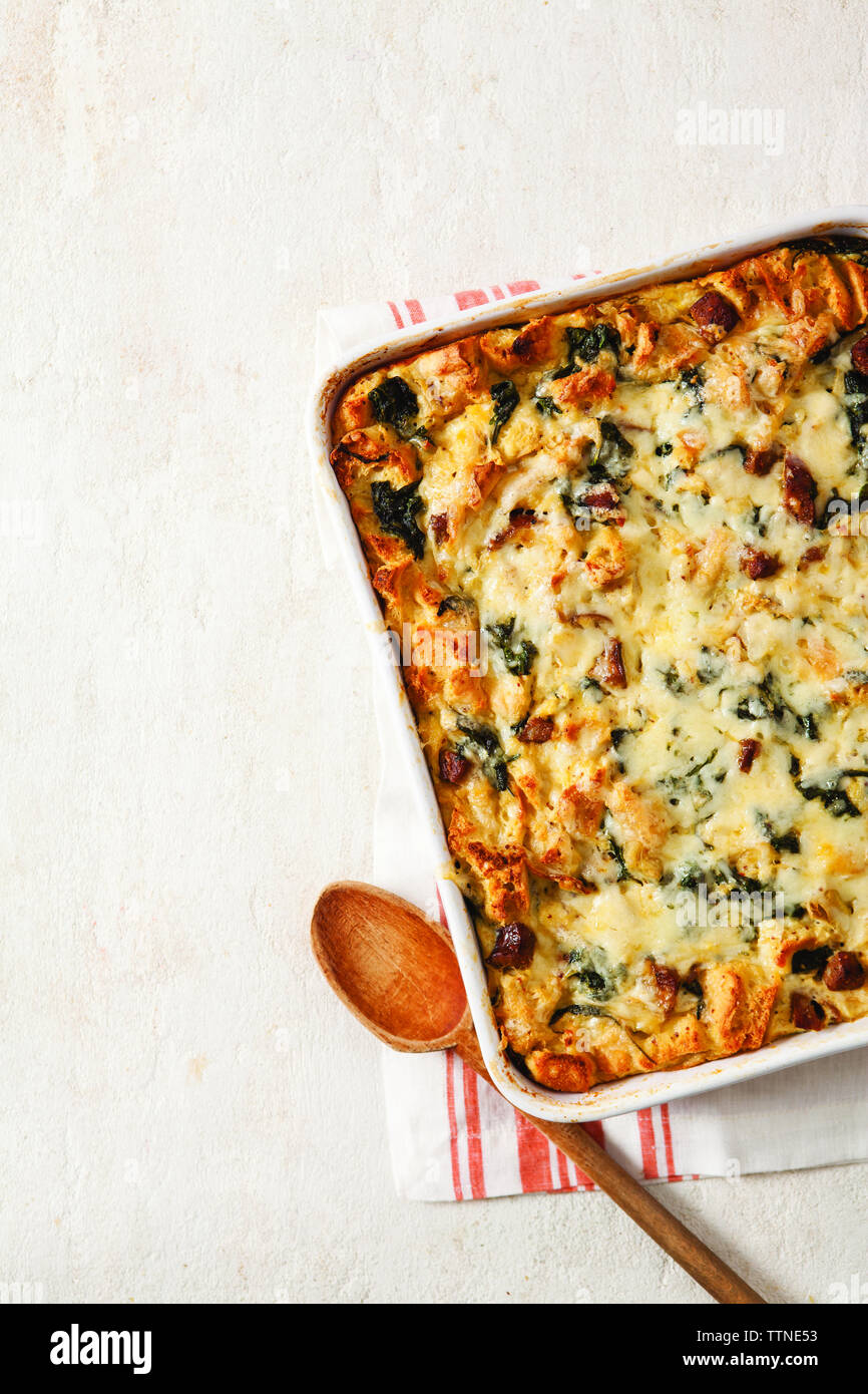High angle view of casserole in container with wooden spoon and napkin ...