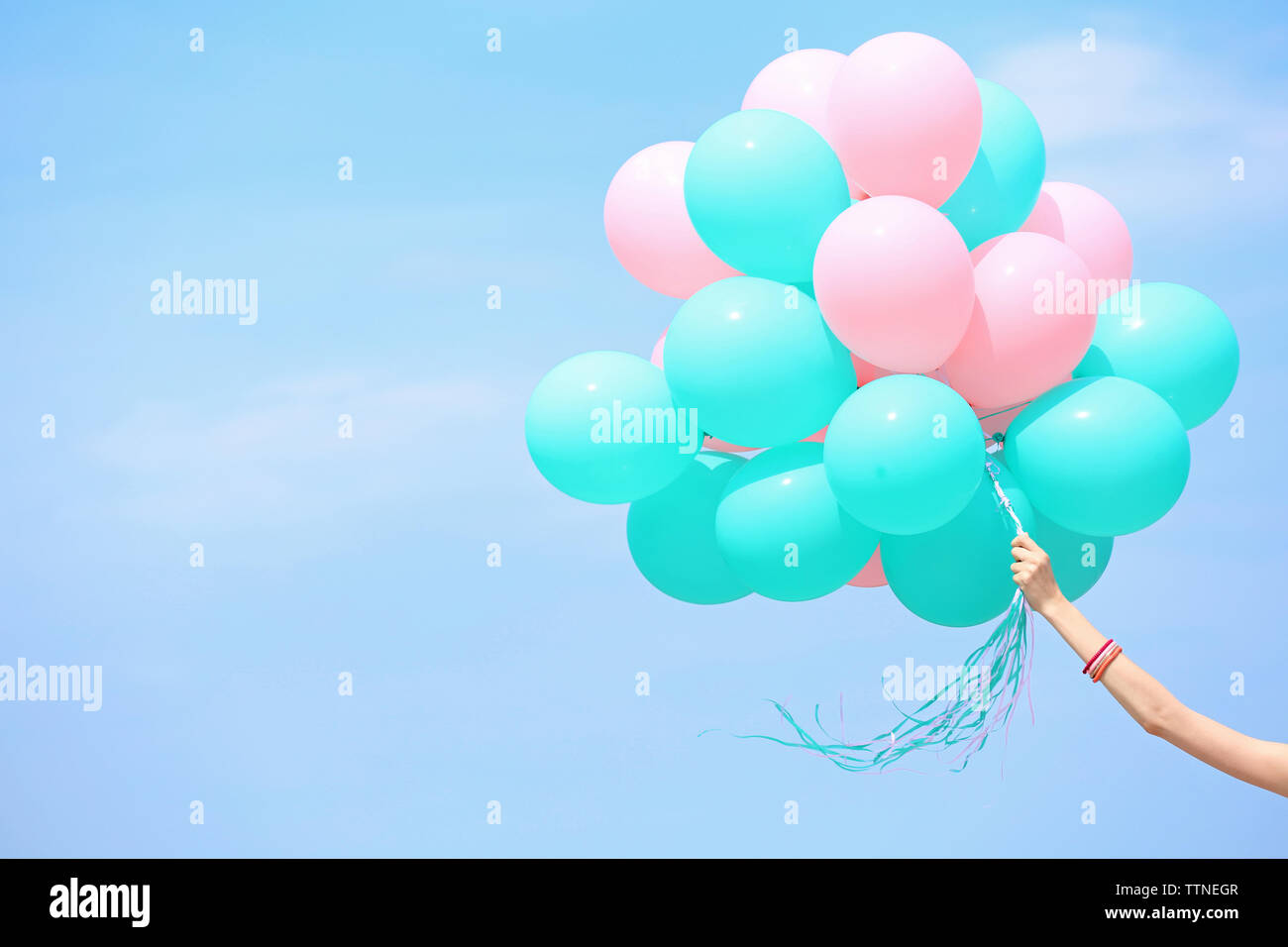 Female hand holding colorful balloons against blue sky Stock Photo - Alamy