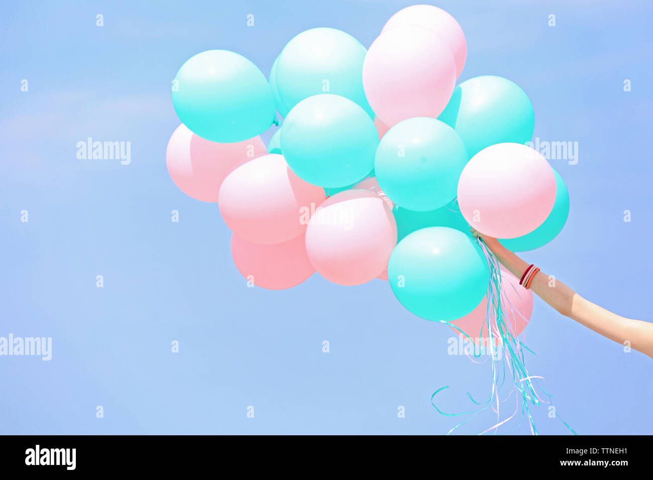 Female hand holding colorful balloons against blue sky Stock Photo - Alamy