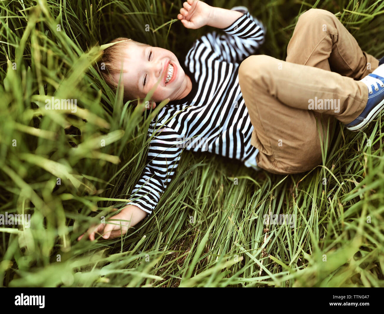 Portrait of a smiling boy lying on the green grass Stock Photo - Alamy