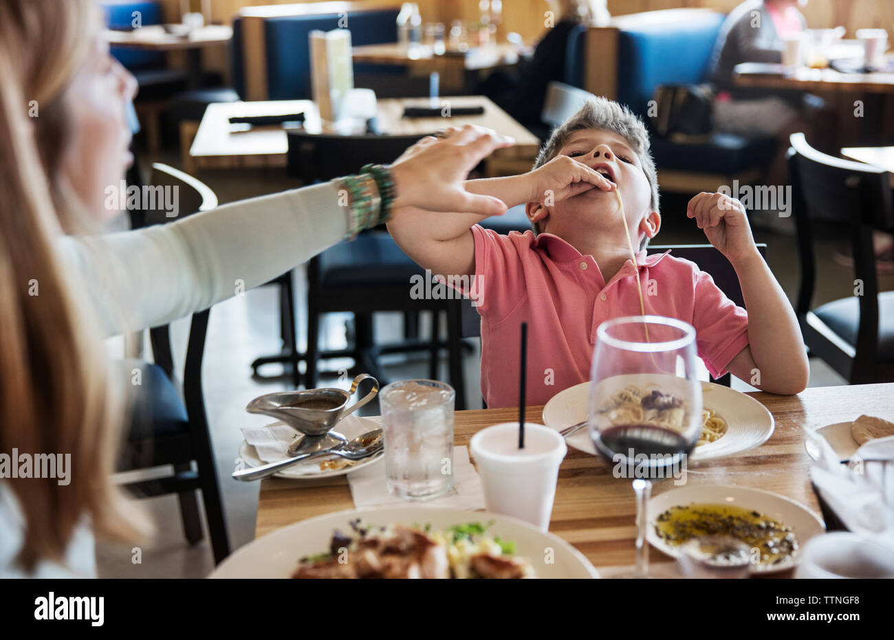 Mother stopping son eating noodles in restaurant Stock Photo - Alamy