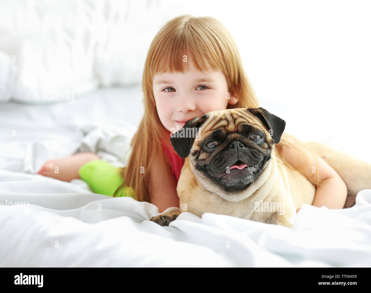 Beautiful girl and cute pug on bed Stock Photo - Alamy