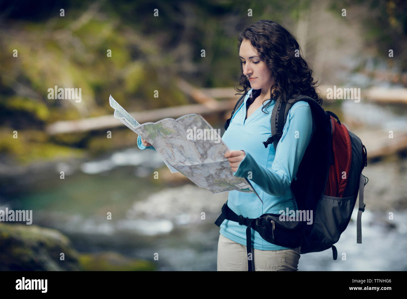 Young woman checking map by stream Stock Photo - Alamy