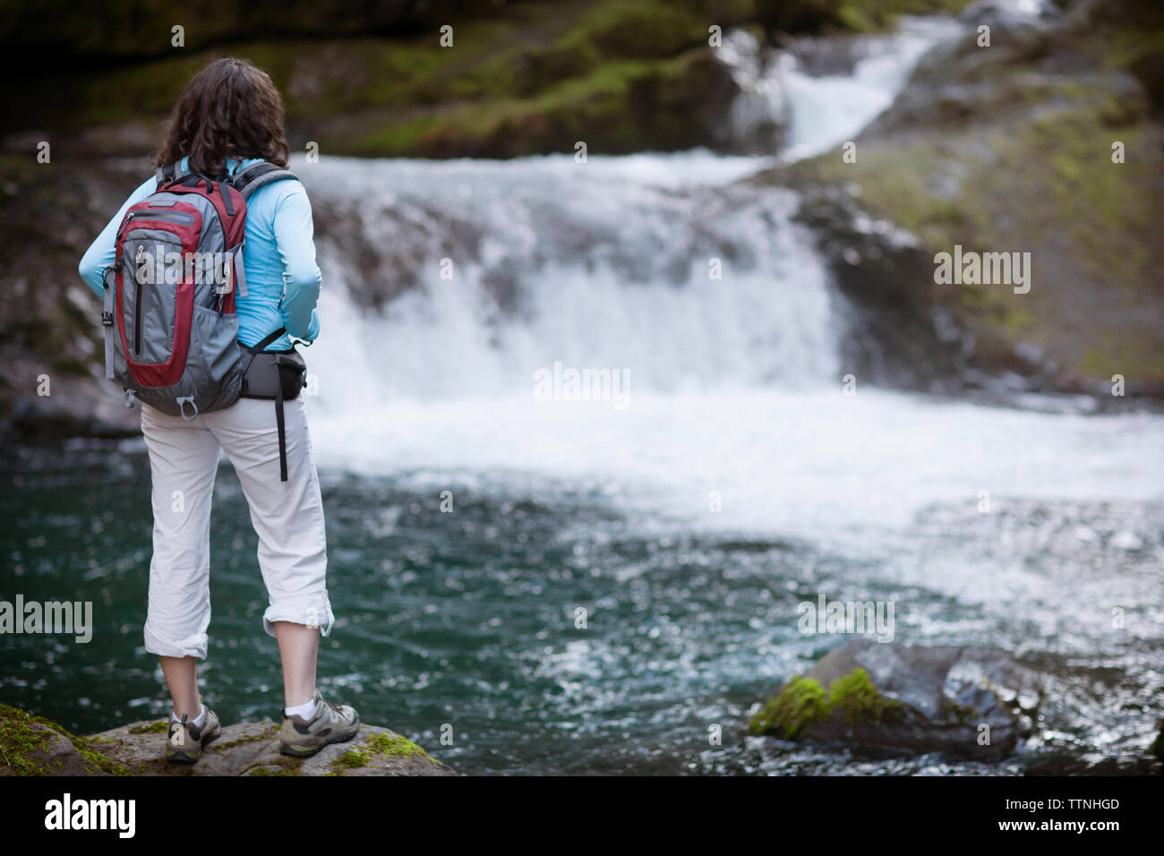 Young woman standing on edge of stream Stock Photo - Alamy