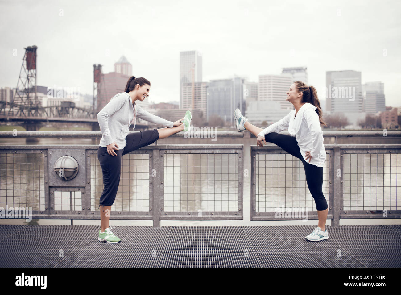 Two young women stretching on railing Stock Photo - Alamy
