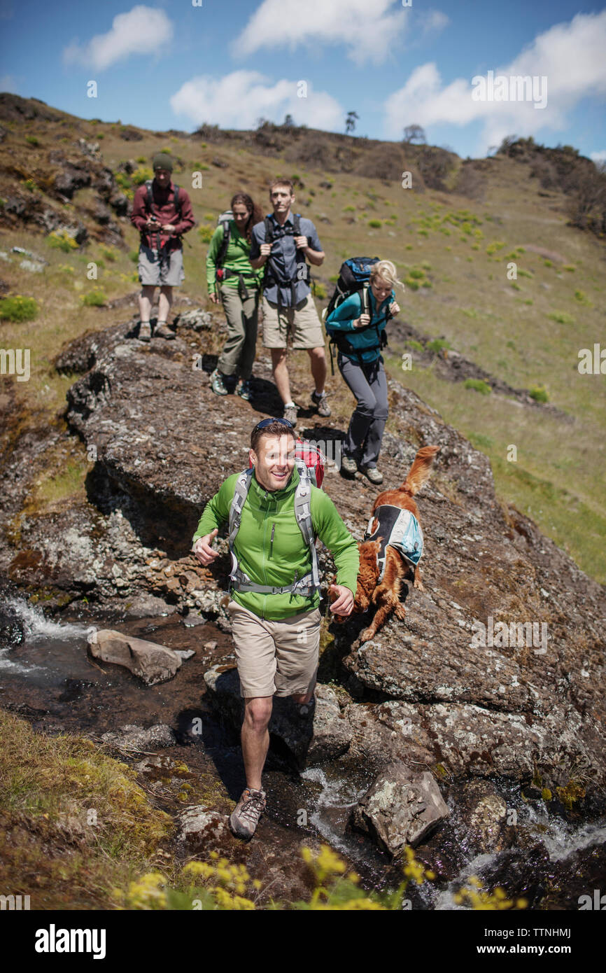 Friends and dog crossing stream on mountain Stock Photo - Alamy