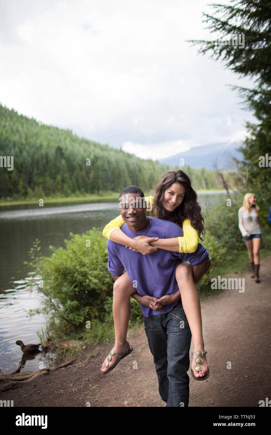 Man piggybacking woman while walking at riverbank Stock Photo - Alamy