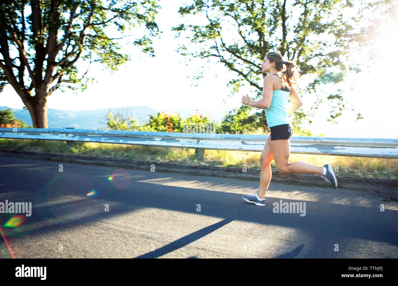 Side view of determined woman running on road during summer Stock Photo ...