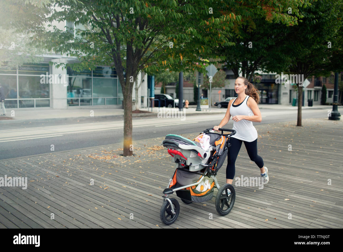 Woman pushing baby stroller while running on floorboard Stock Photo - Alamy