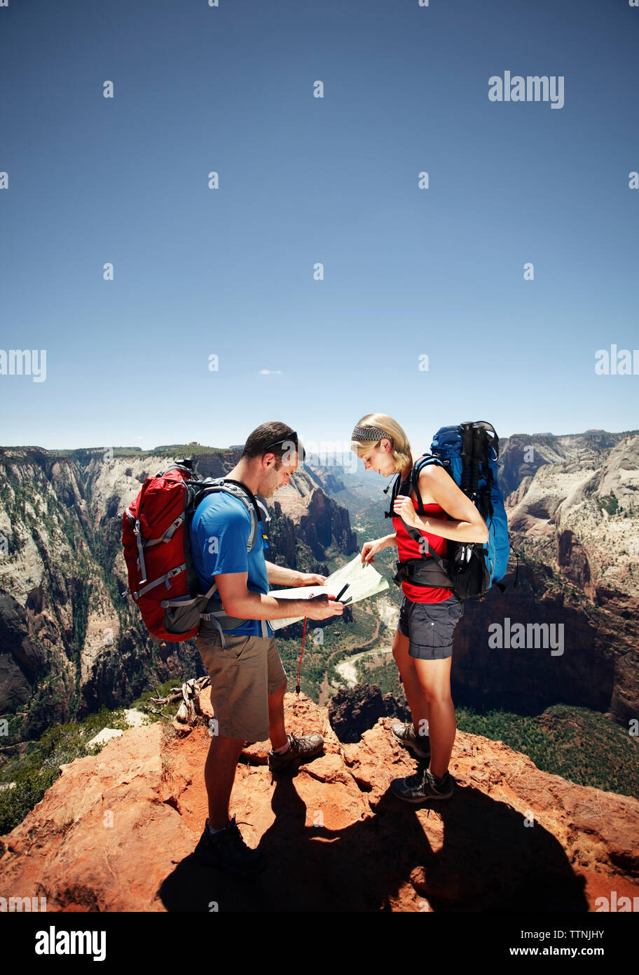Hikers checking map at mountain cliff against clear sky Stock Photo - Alamy