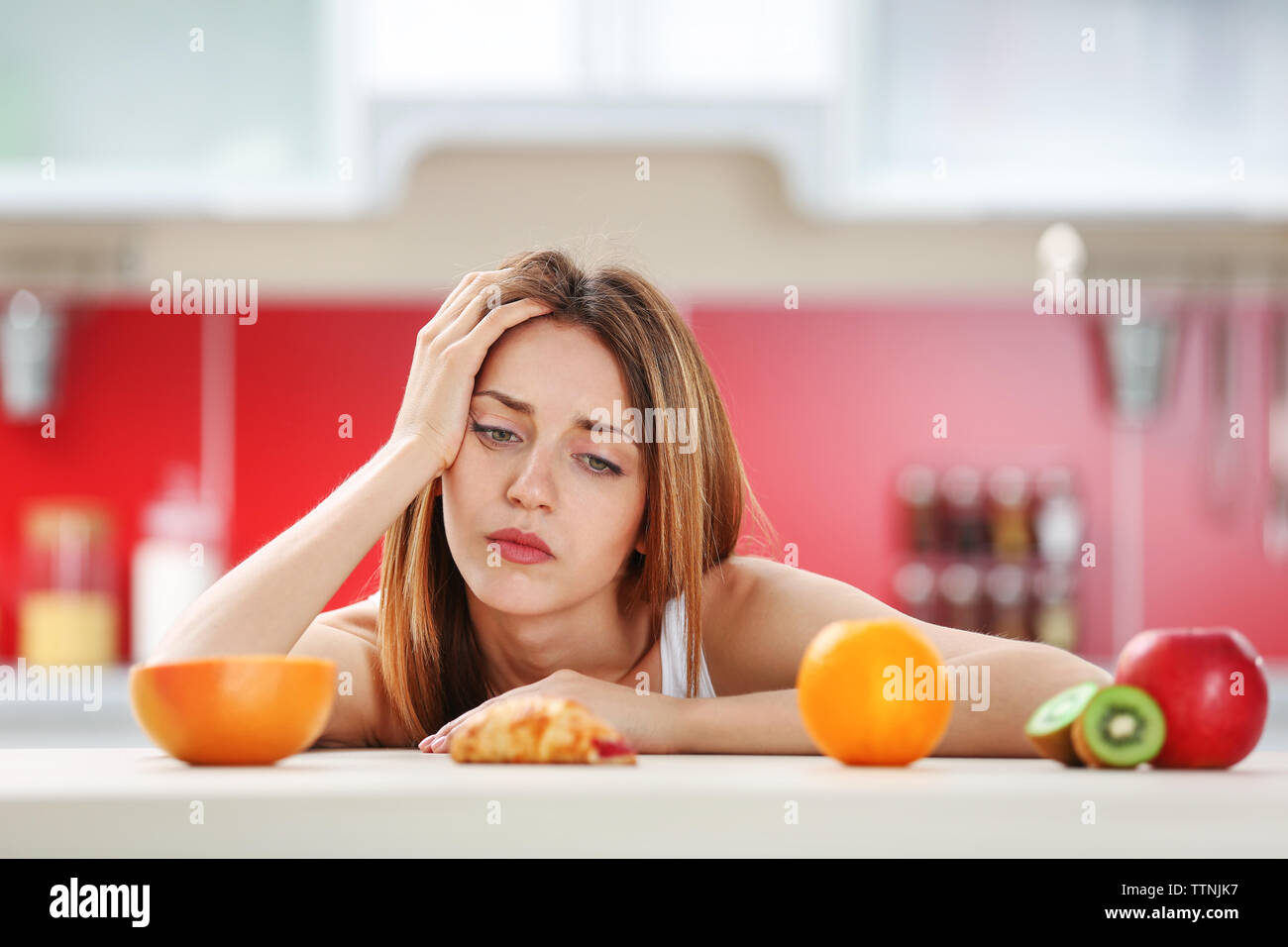 Woman looking guilty at croissant lying among fruits Stock Photo - Alamy