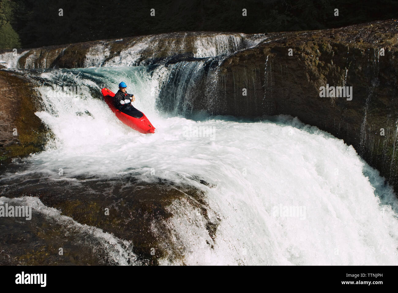 Kayaker paddling through waterfall Stock Photo - Alamy