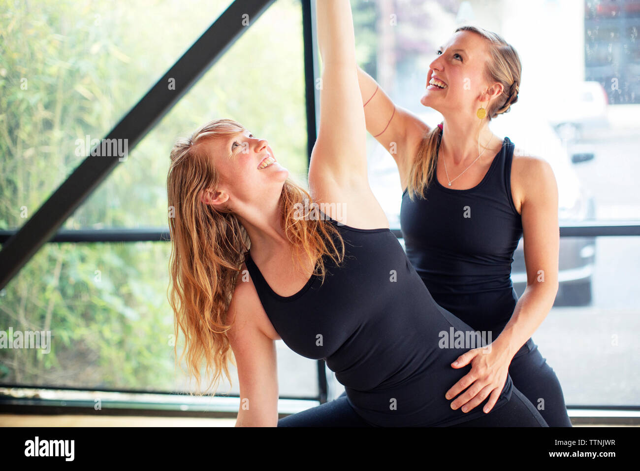 Instructor assisting woman in yoga posture at studio Stock Photo - Alamy