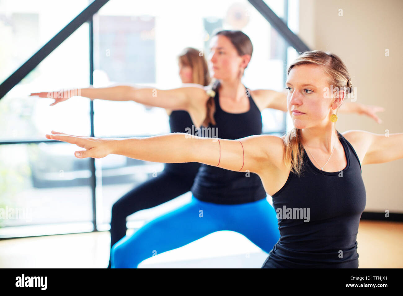 Friends practicing warrior pose in yoga class Stock Photo - Alamy