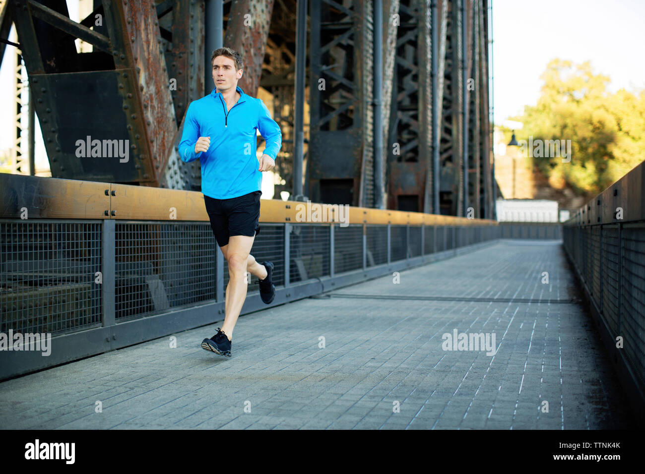 Full length of man running while exercising on bridge in city Stock ...
