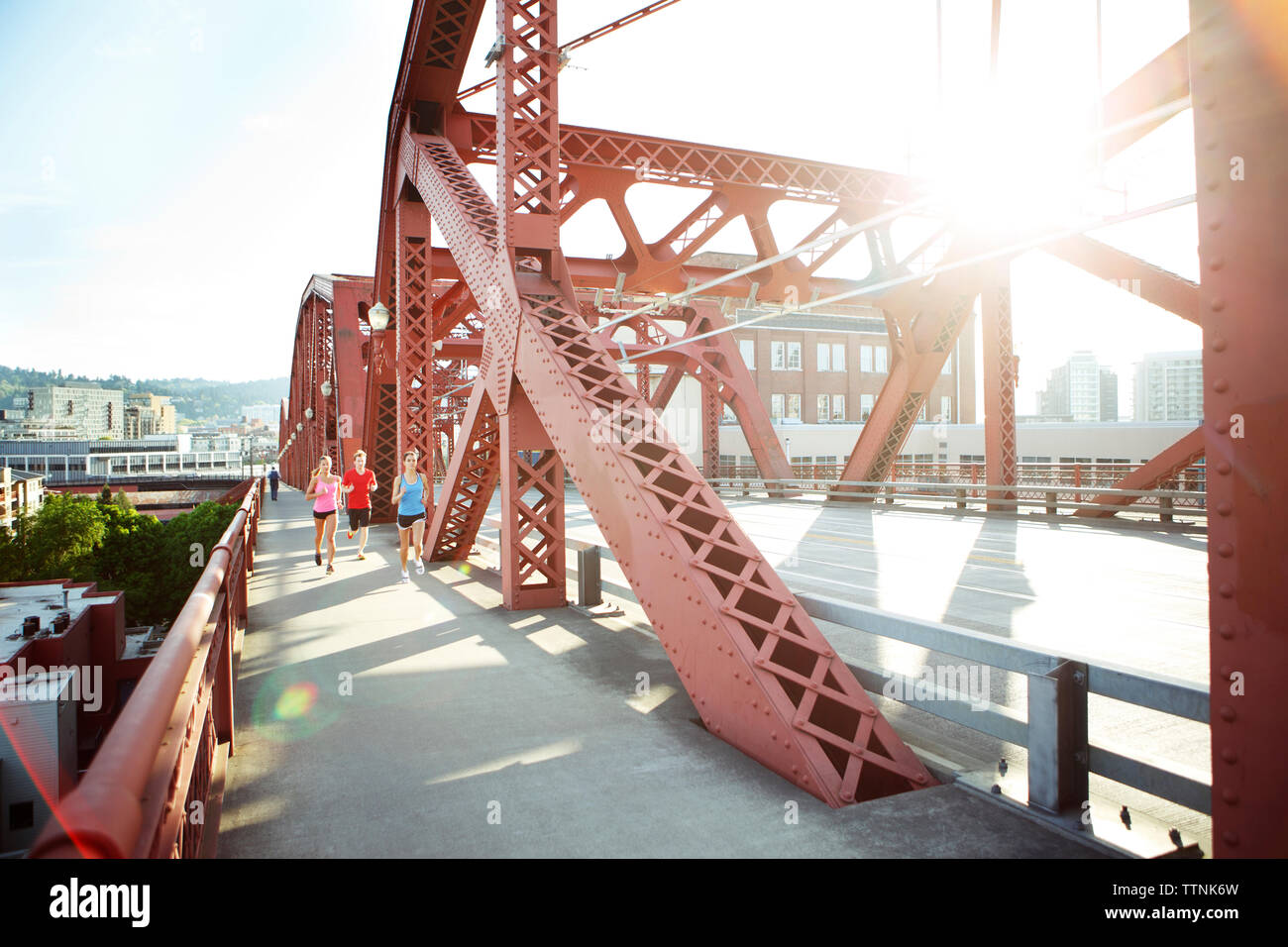 Athlete friends running on footbridge during sunny day Stock Photo - Alamy