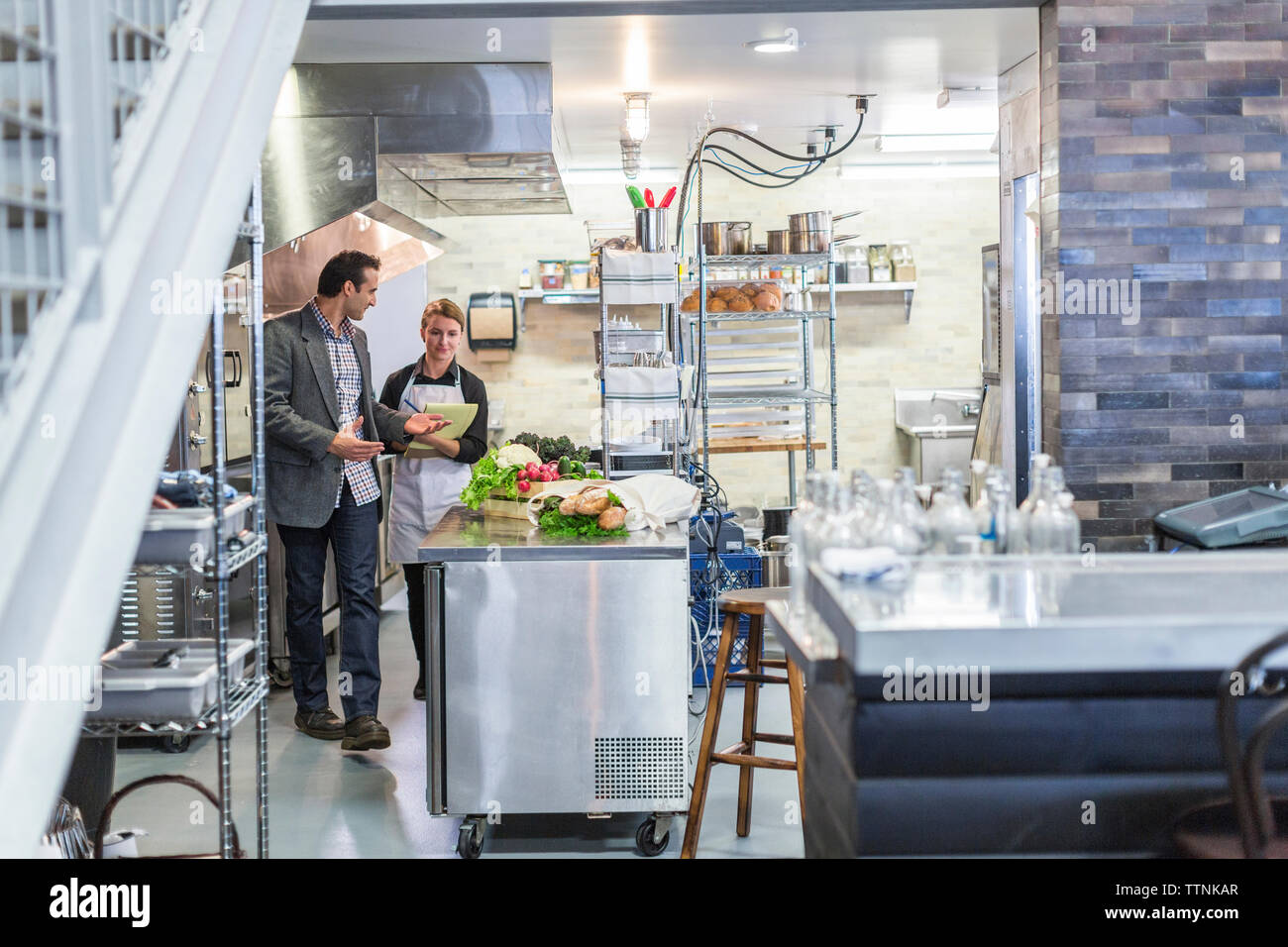 Owner discussing with female chef at restaurant kitchen Stock Photo - Alamy
