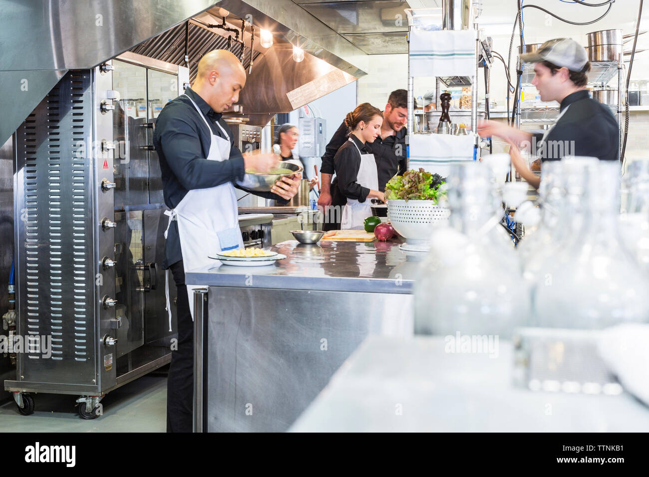 Chefs preparing food in commercial kitchen at restaurant Stock Photo ...