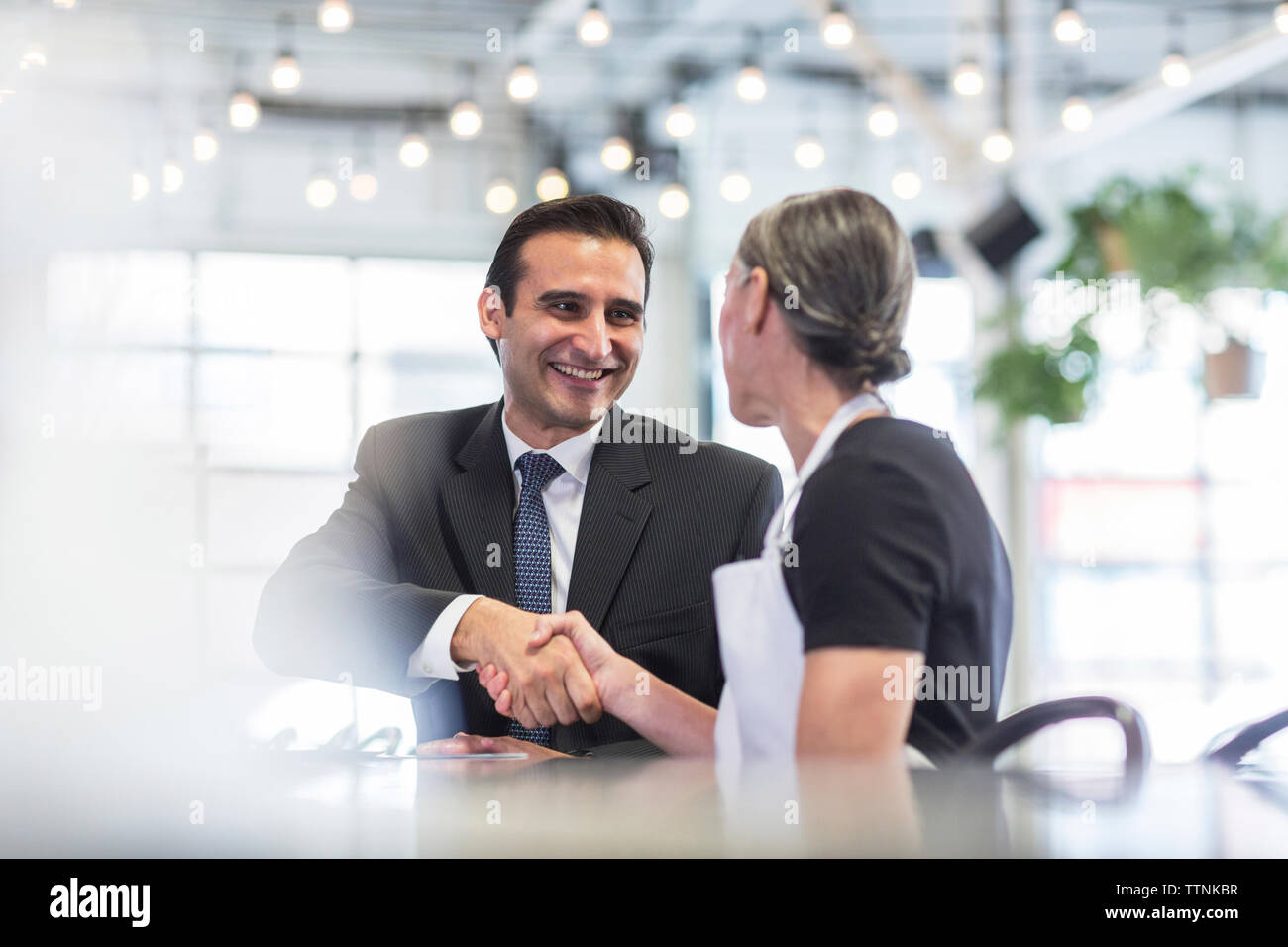 businessman giving handshake to female chef at table in restaurant Stock Photo - Alamy