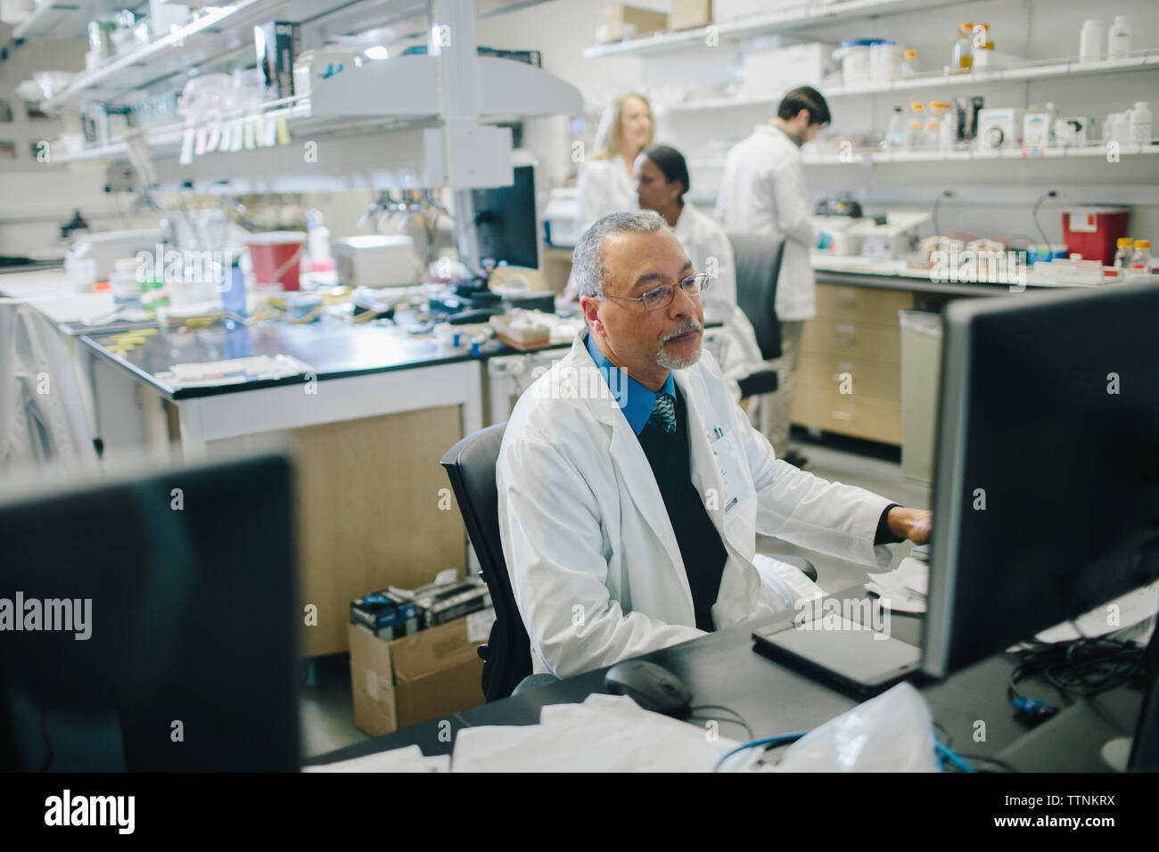 Male doctor using desktop computer while coworkers working in ...