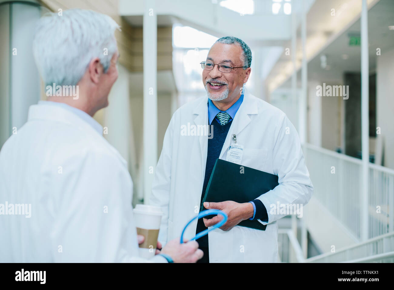 Male doctors talking while standing in hospital corridor Stock Photo ...