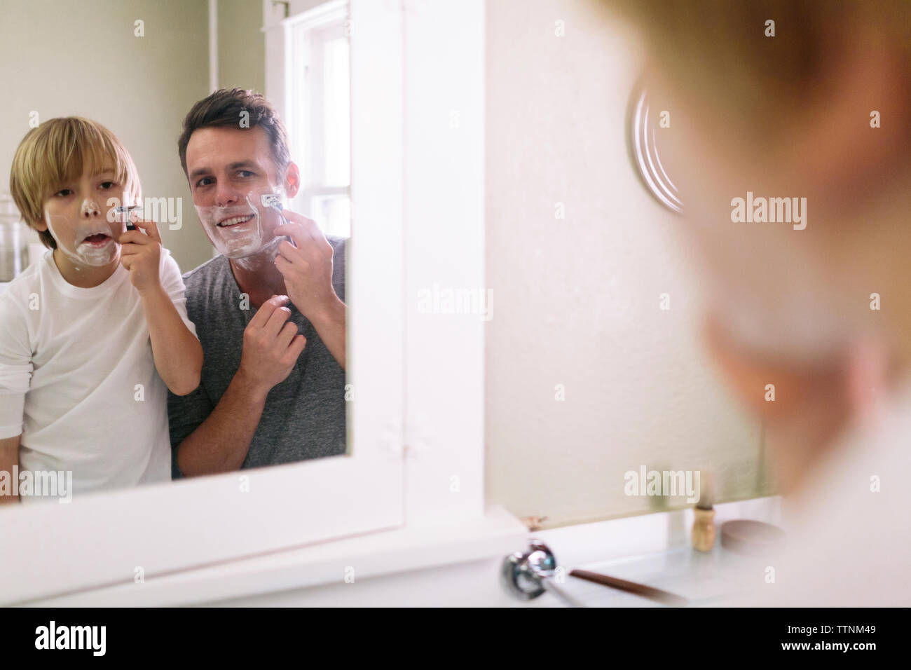 Father and son shaving while reflecting in mirror Stock Photo - Alamy