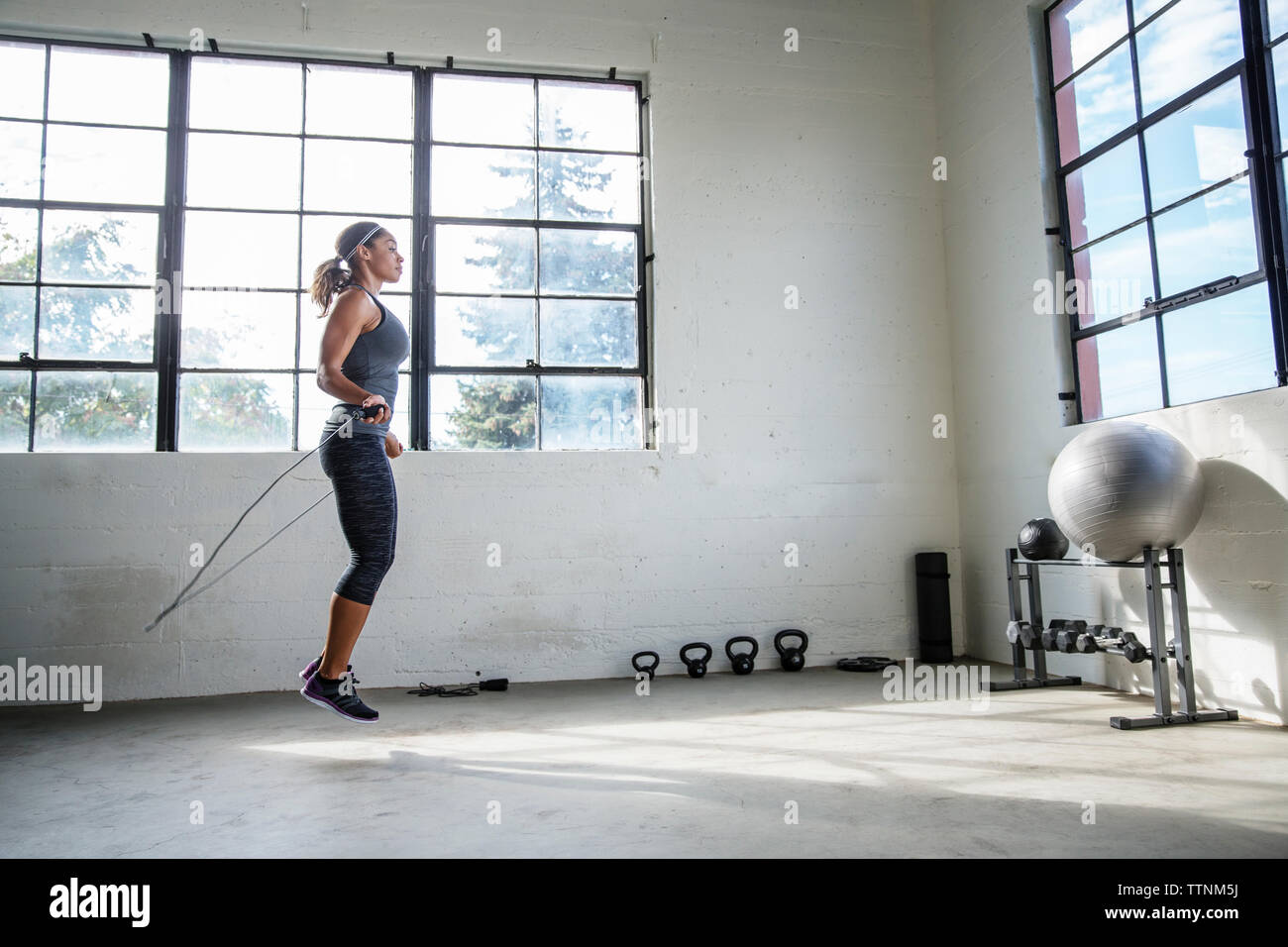 Side view of female athlete skipping with jumping rope in gym Stock ...
