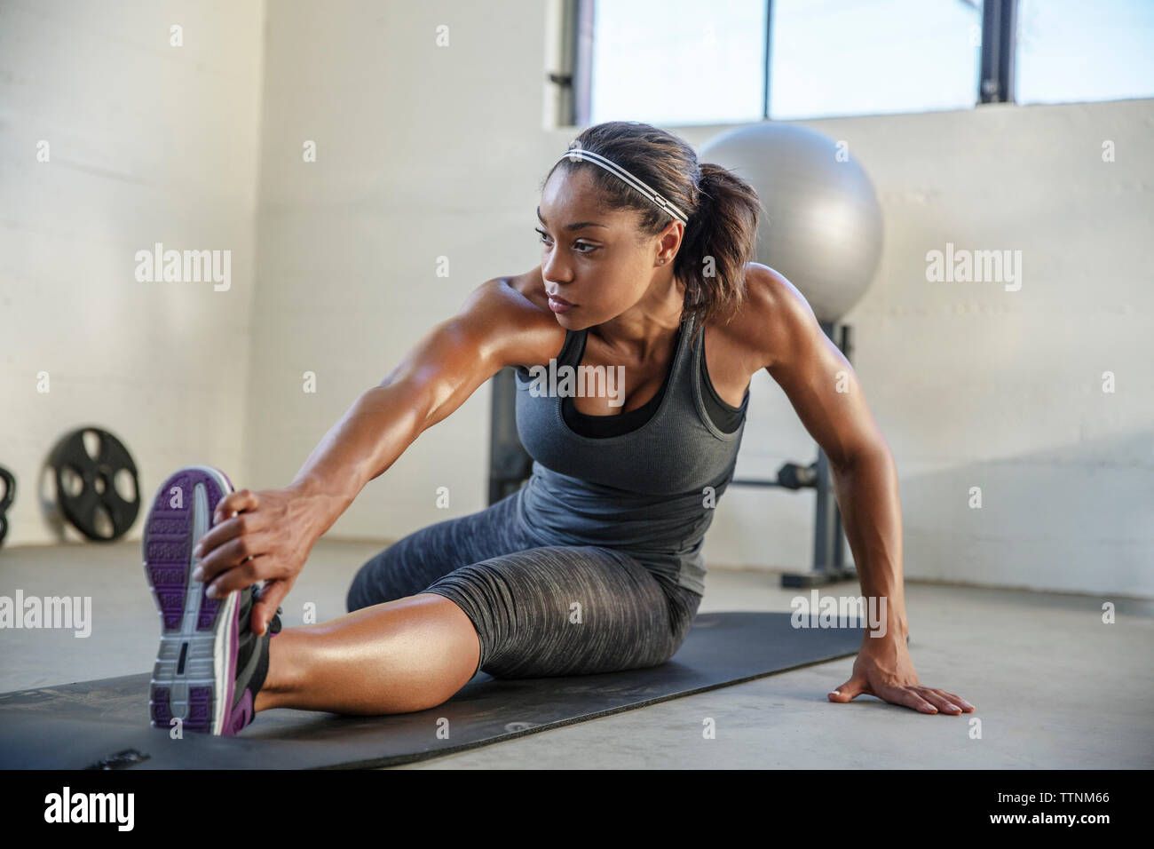 Female athlete stretching legs on exercise mat in health club Stock ...
