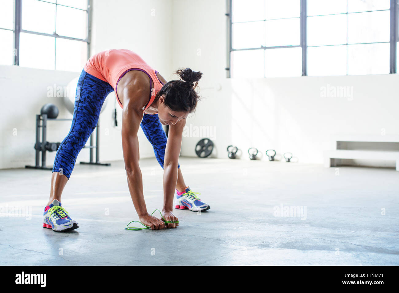 Female athlete bending while exercising with jumping rope in gym Stock ...