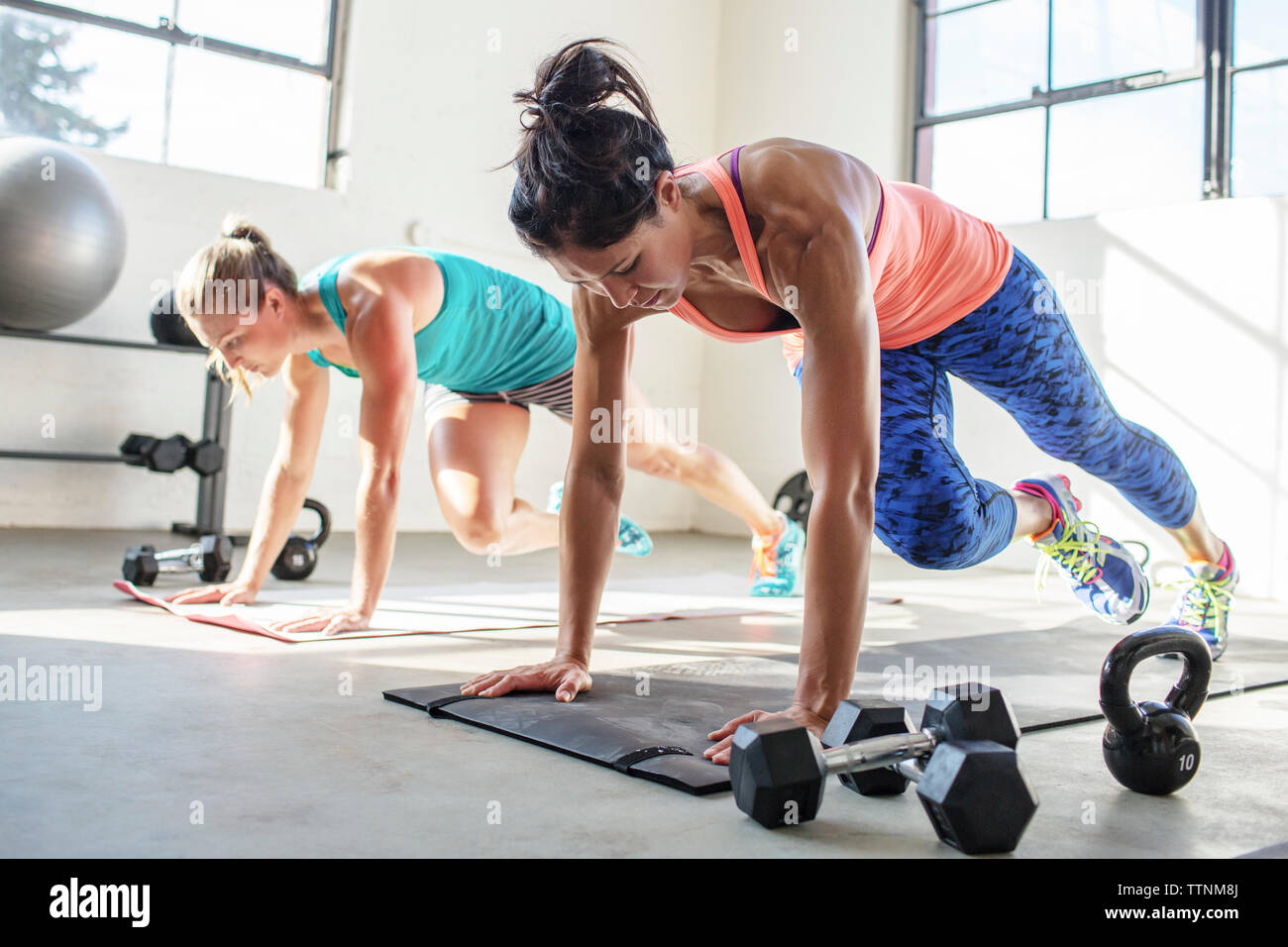 Female athletes doing push-ups on exercise mats in gym Stock Photo - Alamy