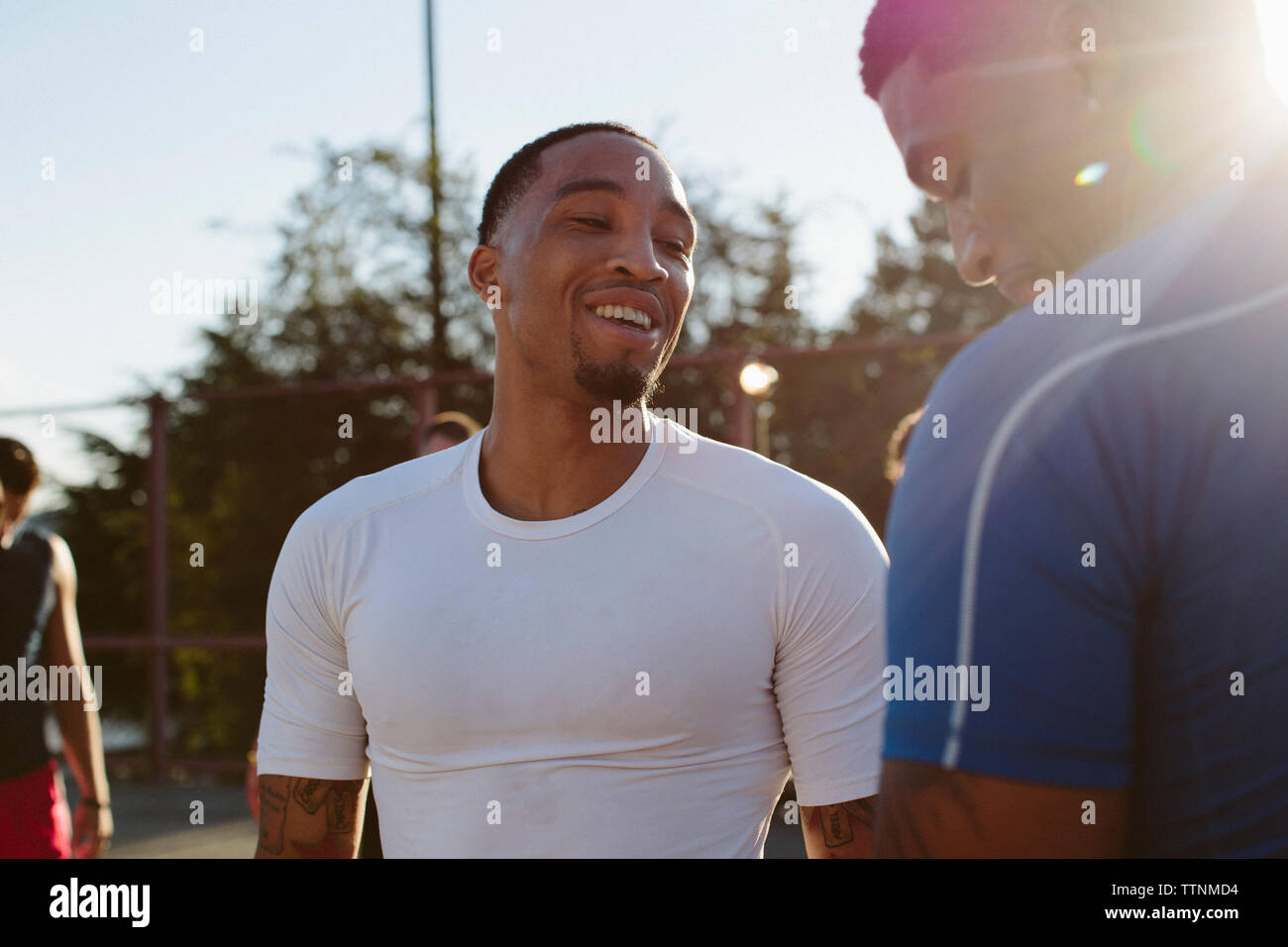 Happy male friends standing at basketball court Stock Photo - Alamy