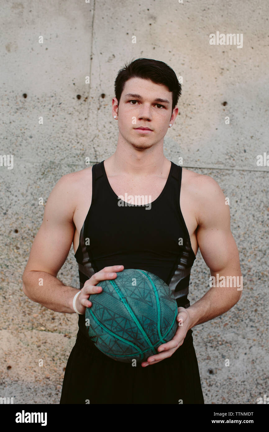 Portrait of man with basketball standing against wall in court Stock ...