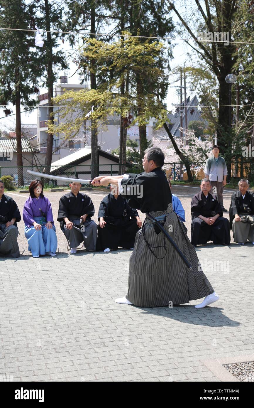 Man in traditional costume demonstrating samurai sword skills outside ...