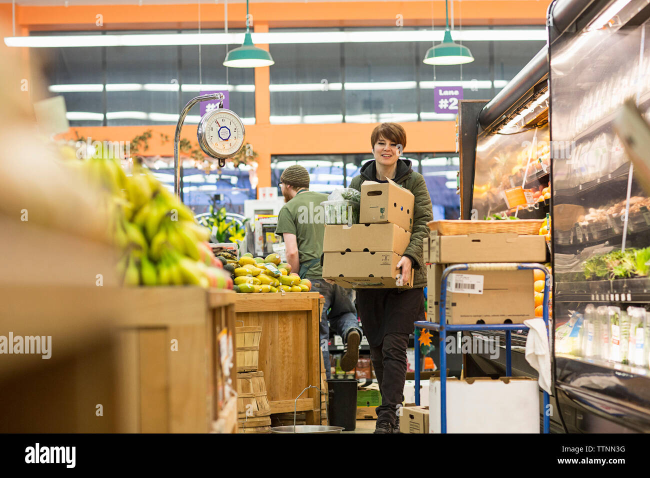 Female worker carrying boxes while working at supermarket Stock Photo ...
