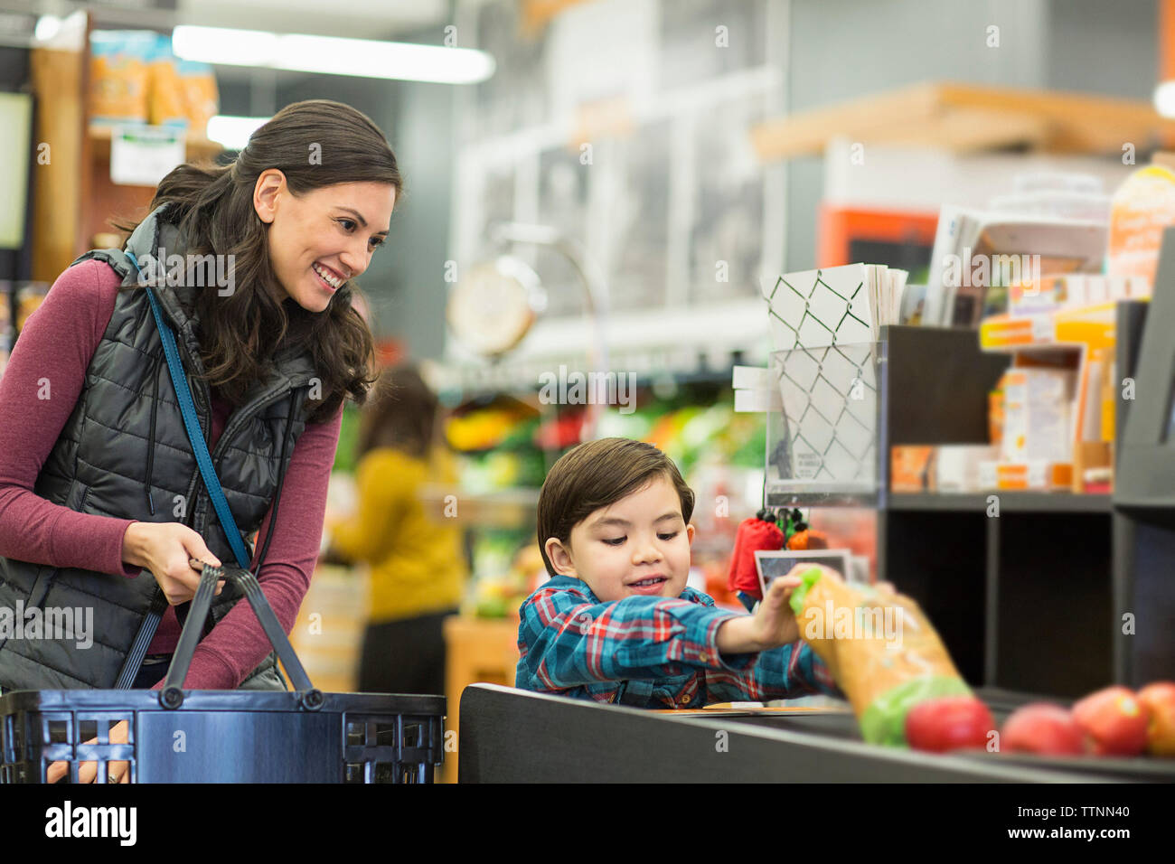 Mother and son keeping food on checkout counter at supermarket Stock ...