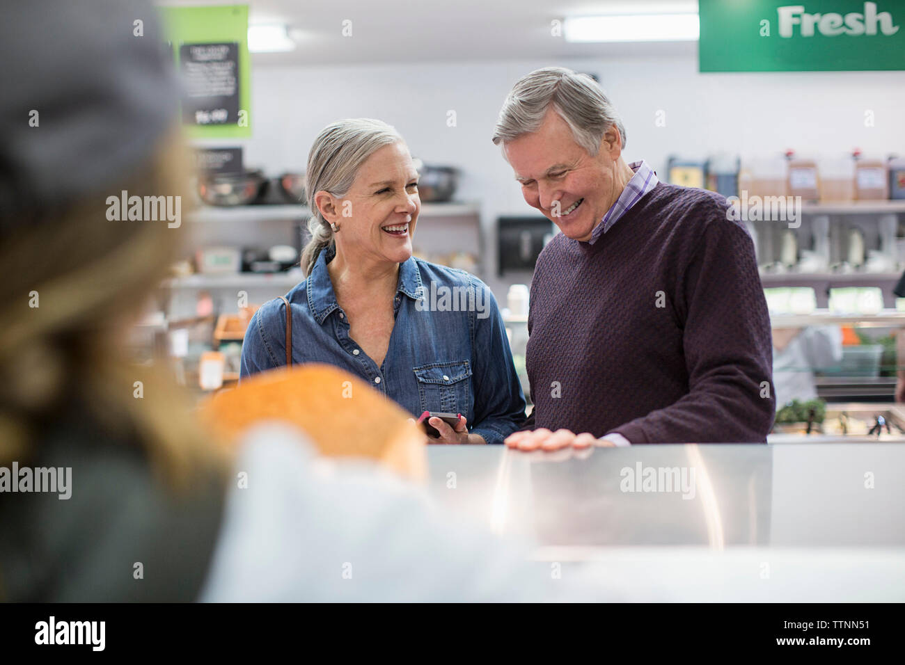 Smiling couple standing by counter at supermarket Stock Photo - Alamy