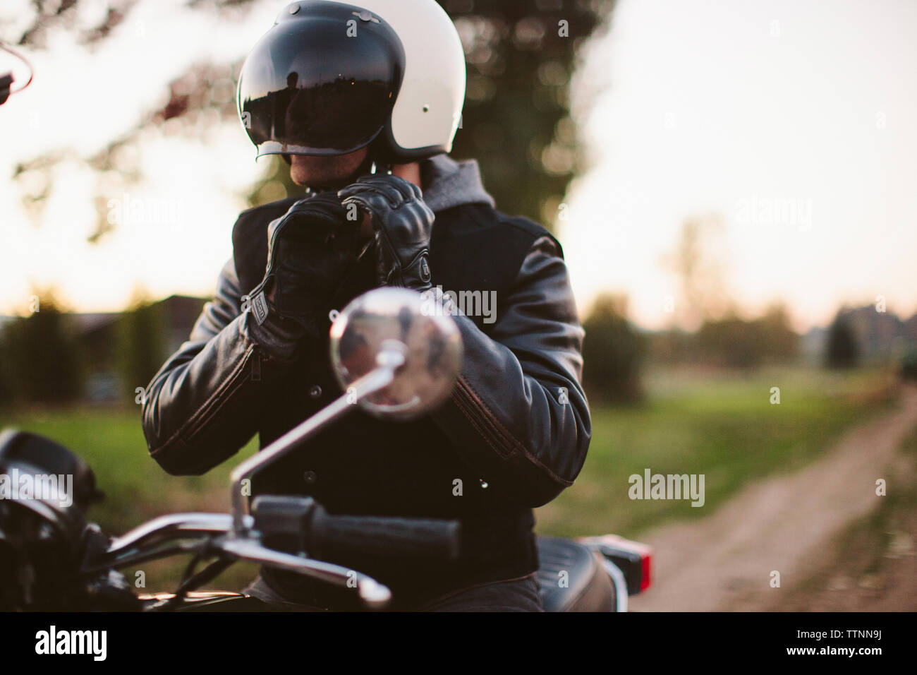 Male biker adjusting helmet while sitting on motorcycle Stock Photo - Alamy