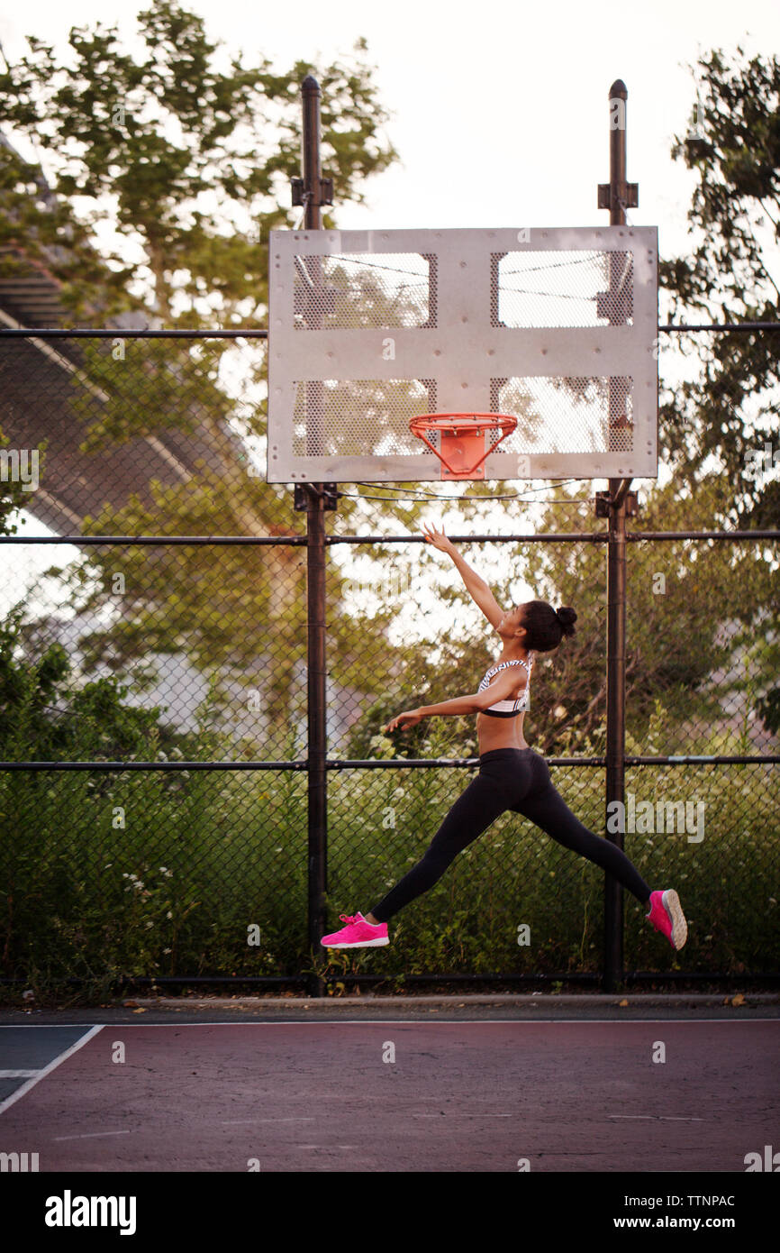 Sporty woman reaching basketball hoop Stock Photo - Alamy