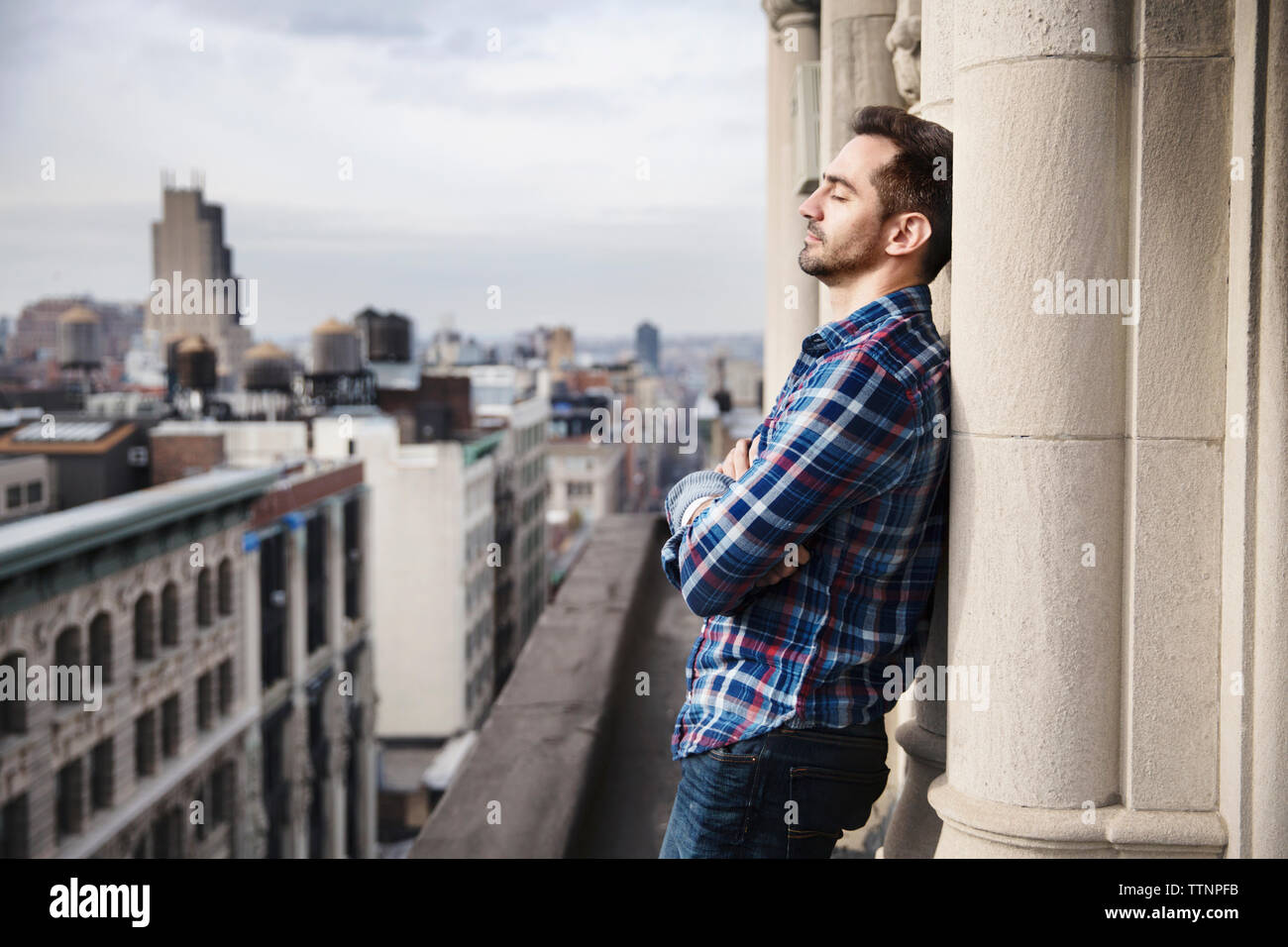 Man leaning on column at balcony against cityscape Stock Photo - Alamy