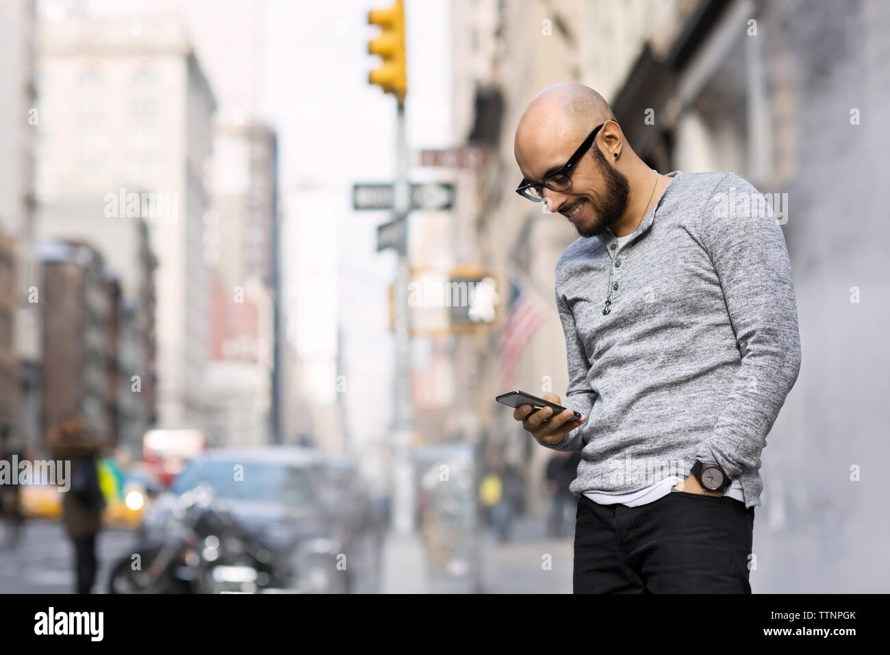 Happy man using smart phone while standing on street Stock Photo - Alamy