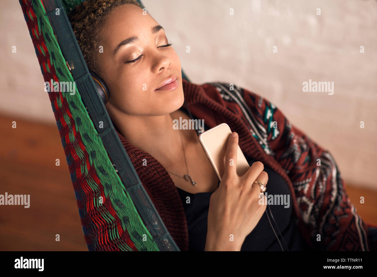 Relaxed woman listening music on hammock at home Stock Photo - Alamy