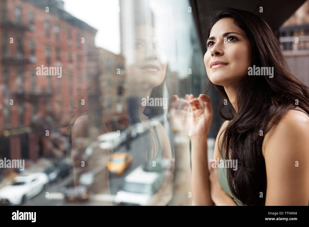 Thoughtful woman looking through glass window Stock Photo - Alamy