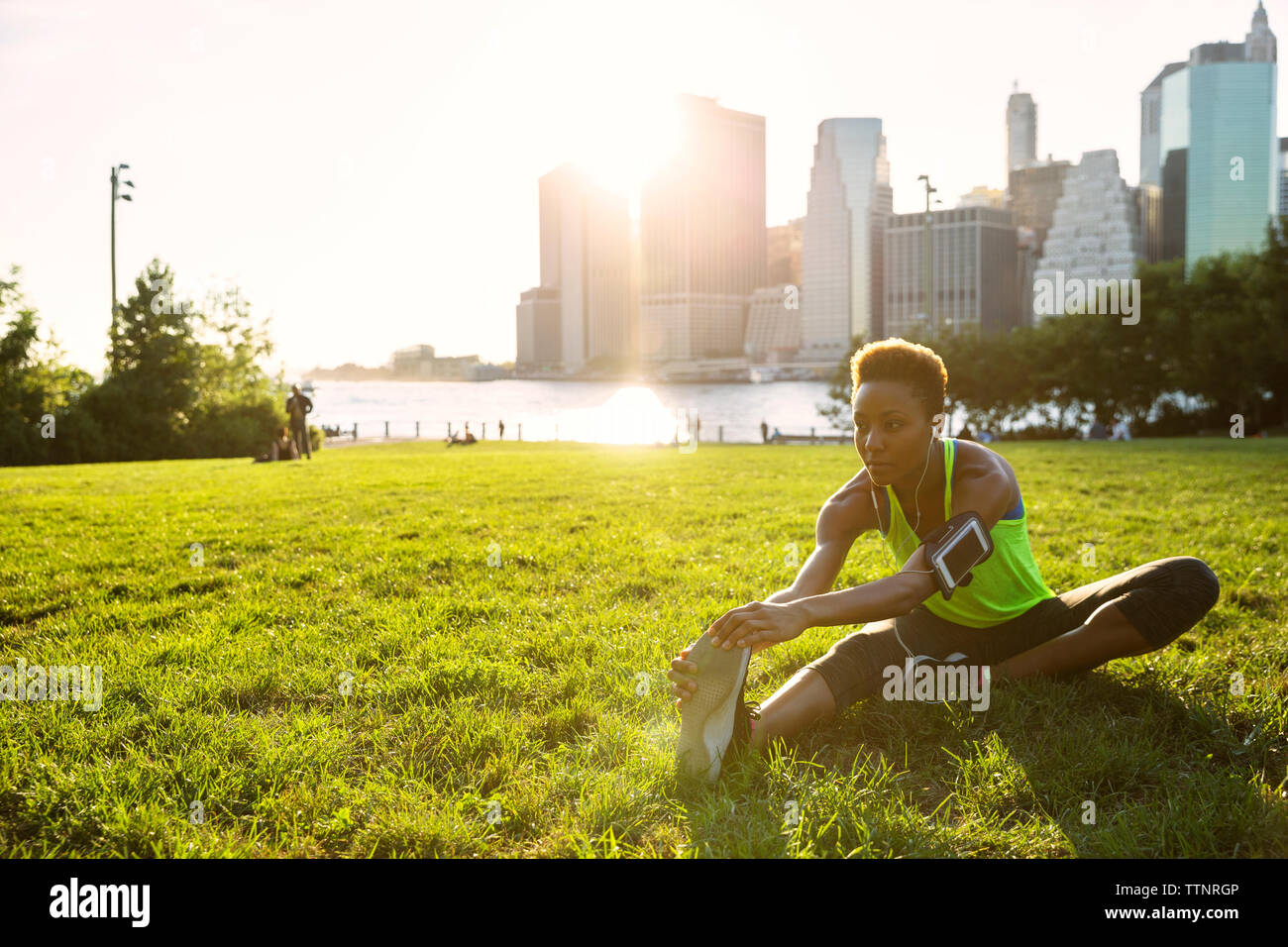Female athlete listening music while exercising on grassy field Stock ...