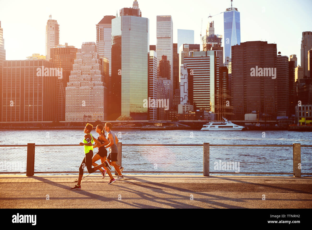 Athletes running on promenade by river Stock Photo - Alamy