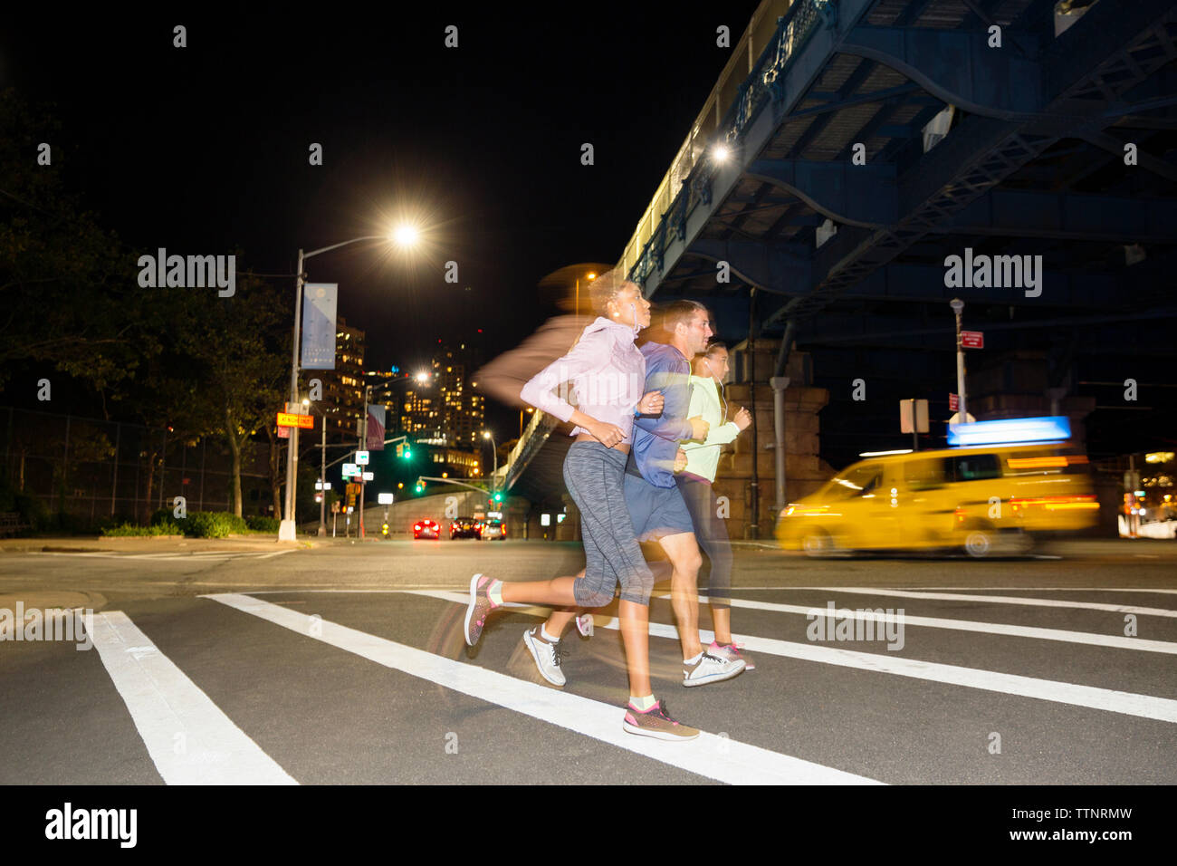 Athlete friends running on street at night Stock Photo - Alamy