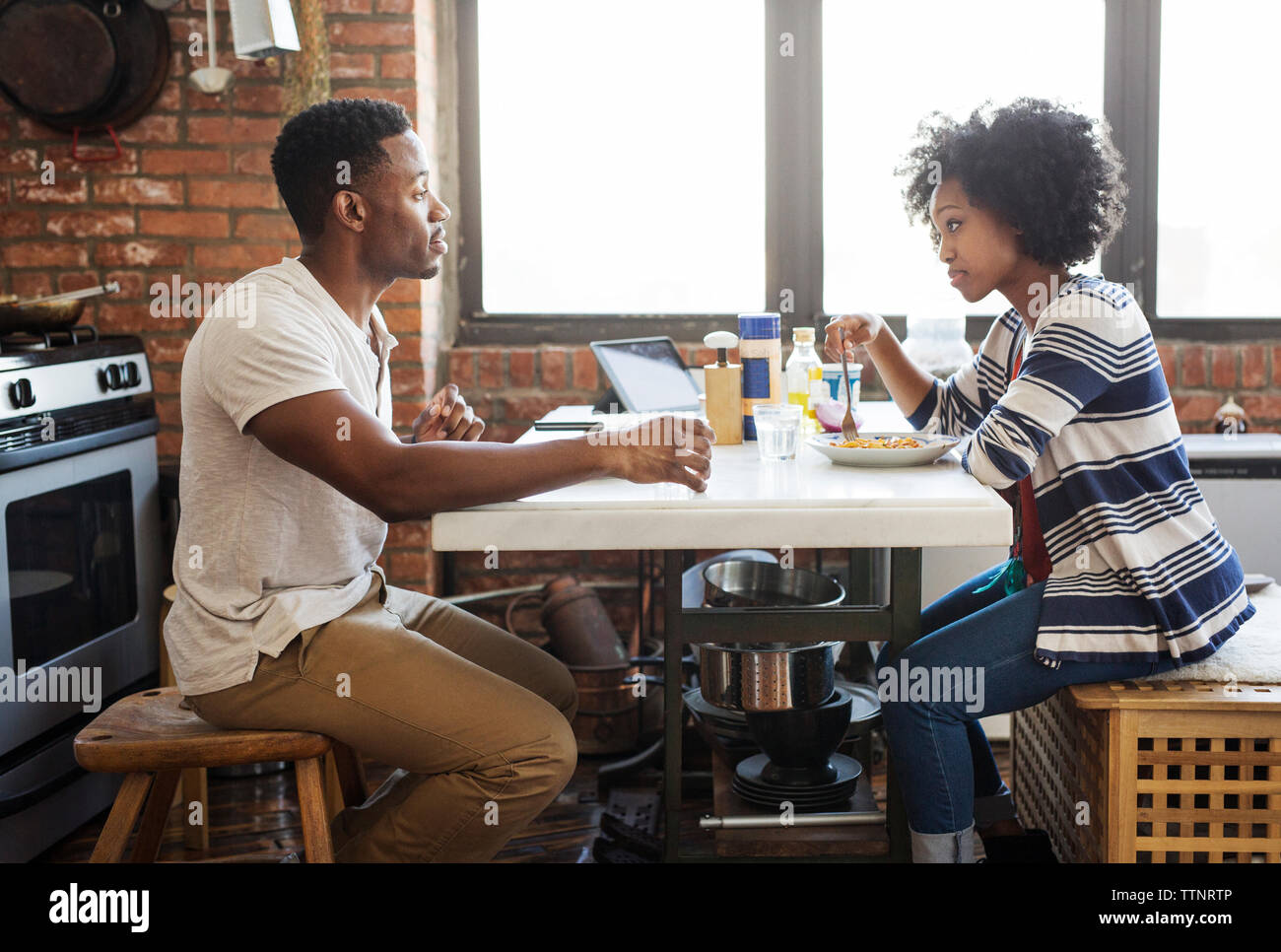 Side view of couple having food at dining table Stock Photo - Alamy
