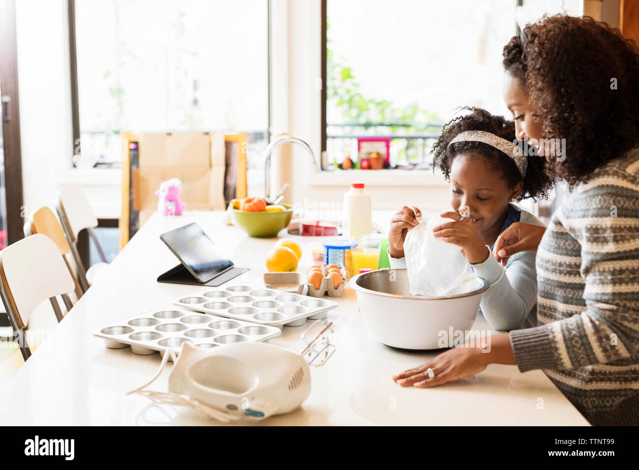 Mother guiding daughter in making cupcakes Stock Photo - Alamy