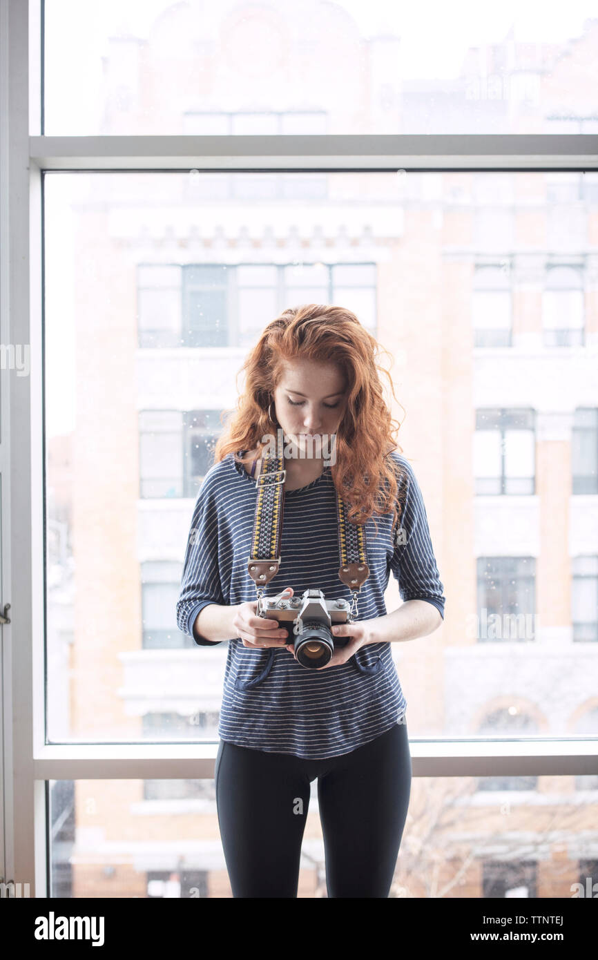 Woman photographing while standing by window at home Stock Photo - Alamy